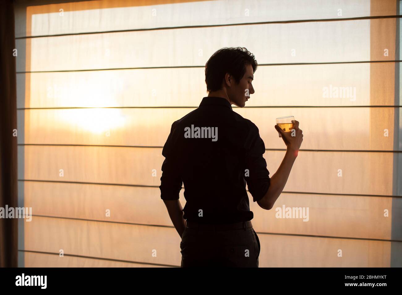 Young Chinese businessman drinking alcohol in front of window Stock ...