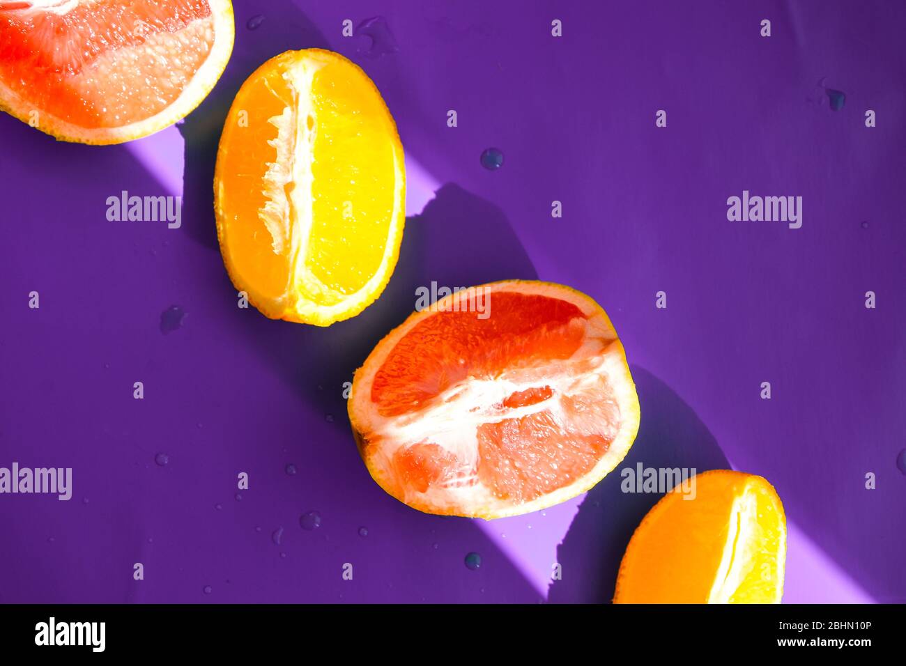 Top view of sliced grapefruits and oranges on blue background with copy space, cut pieces of ...