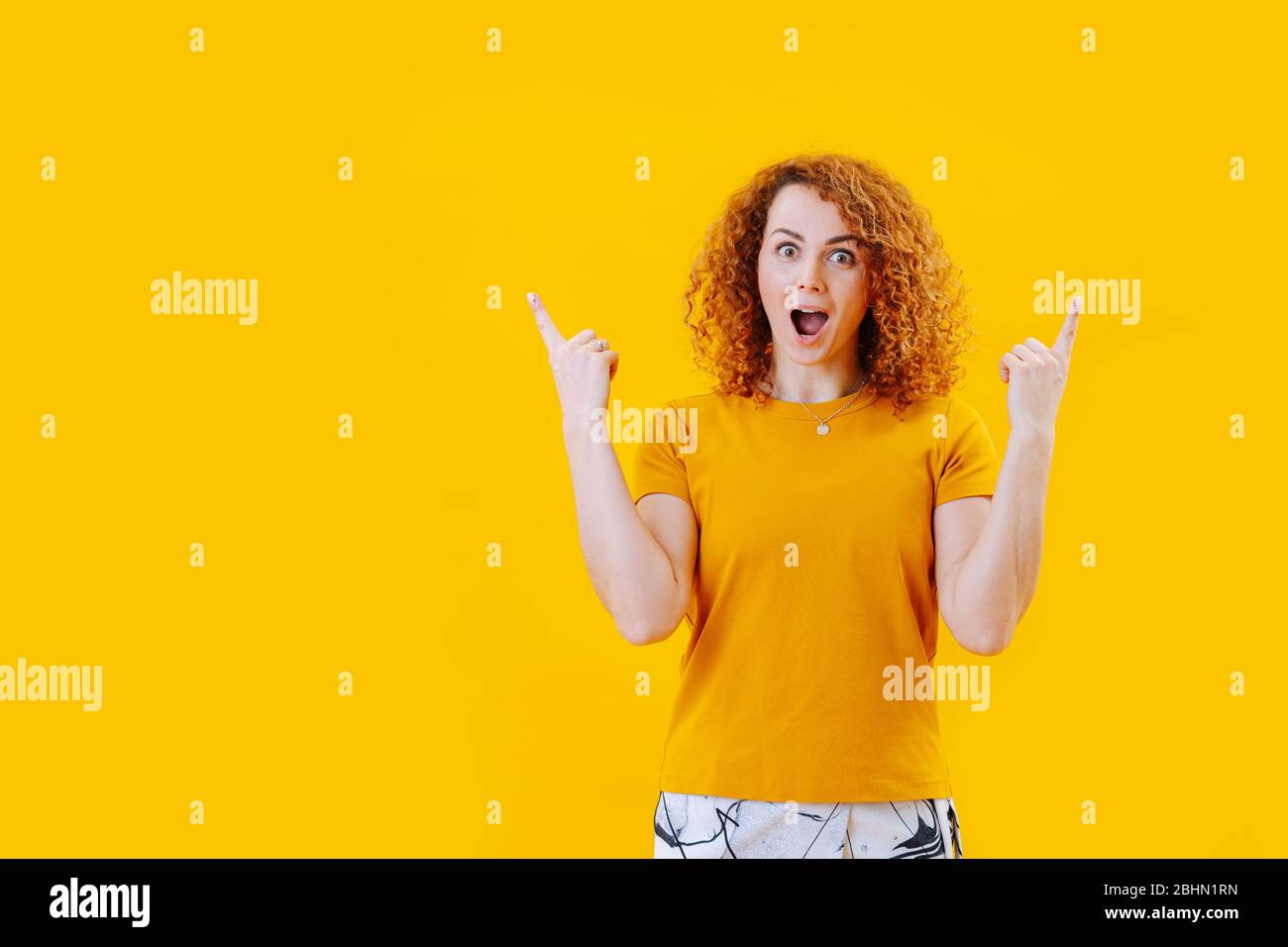 Young woman exhilarated by discovery over yellow background Stock Photo ...