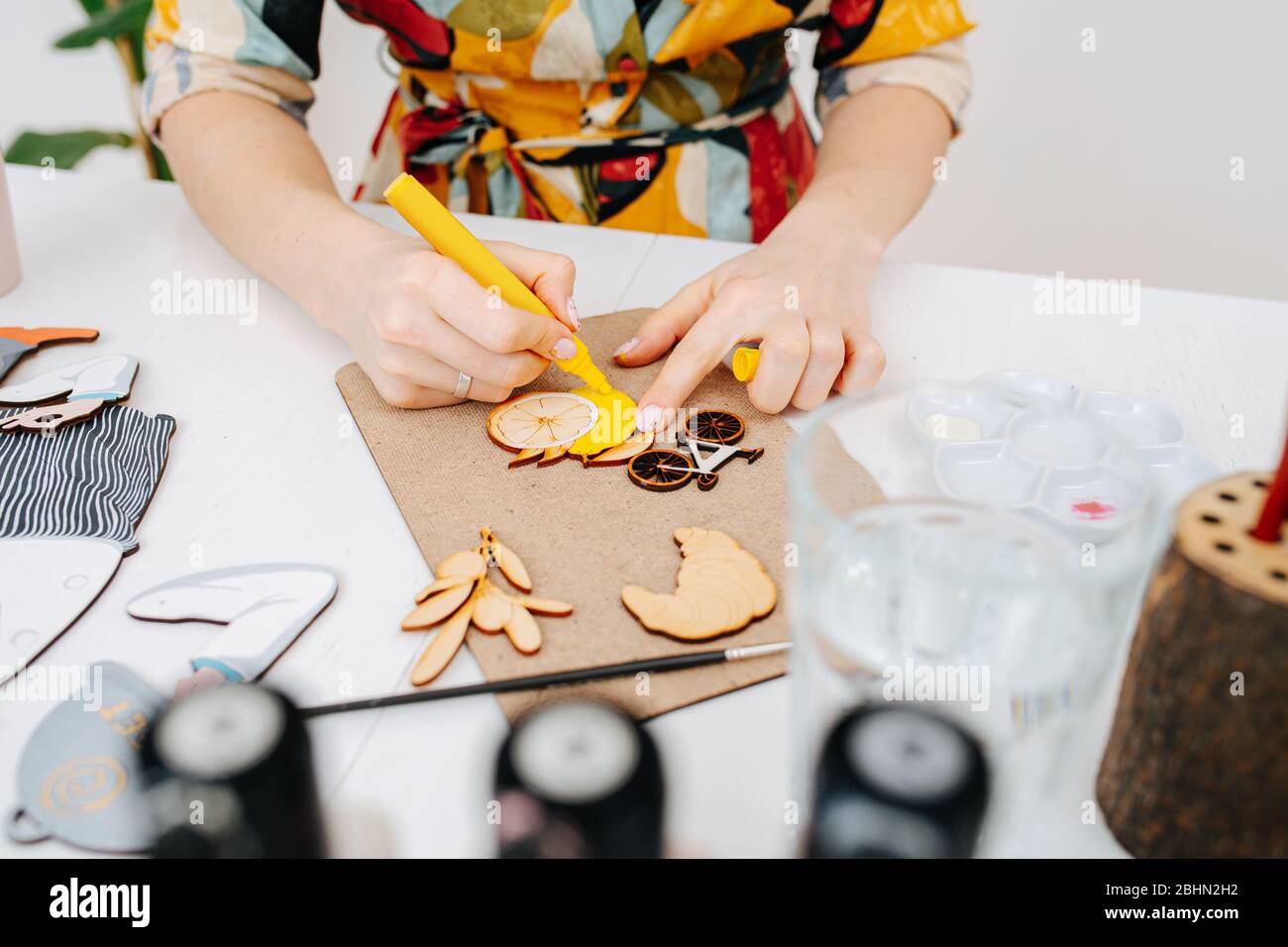 Woman hands painting plywood figures on the work desk with a felt pen ...