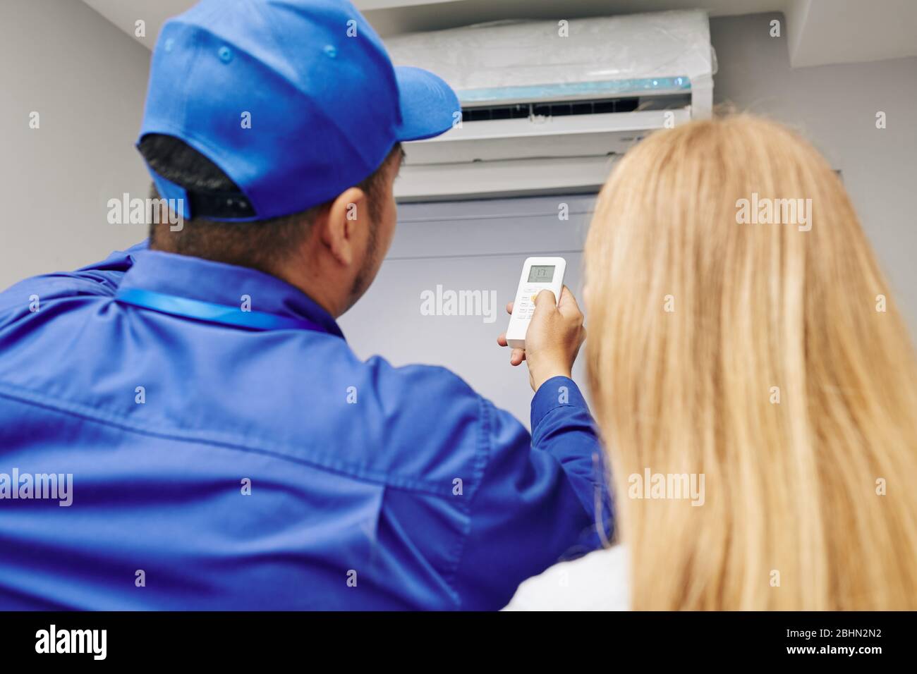 Service worker explaining female customer how use remote control to ...