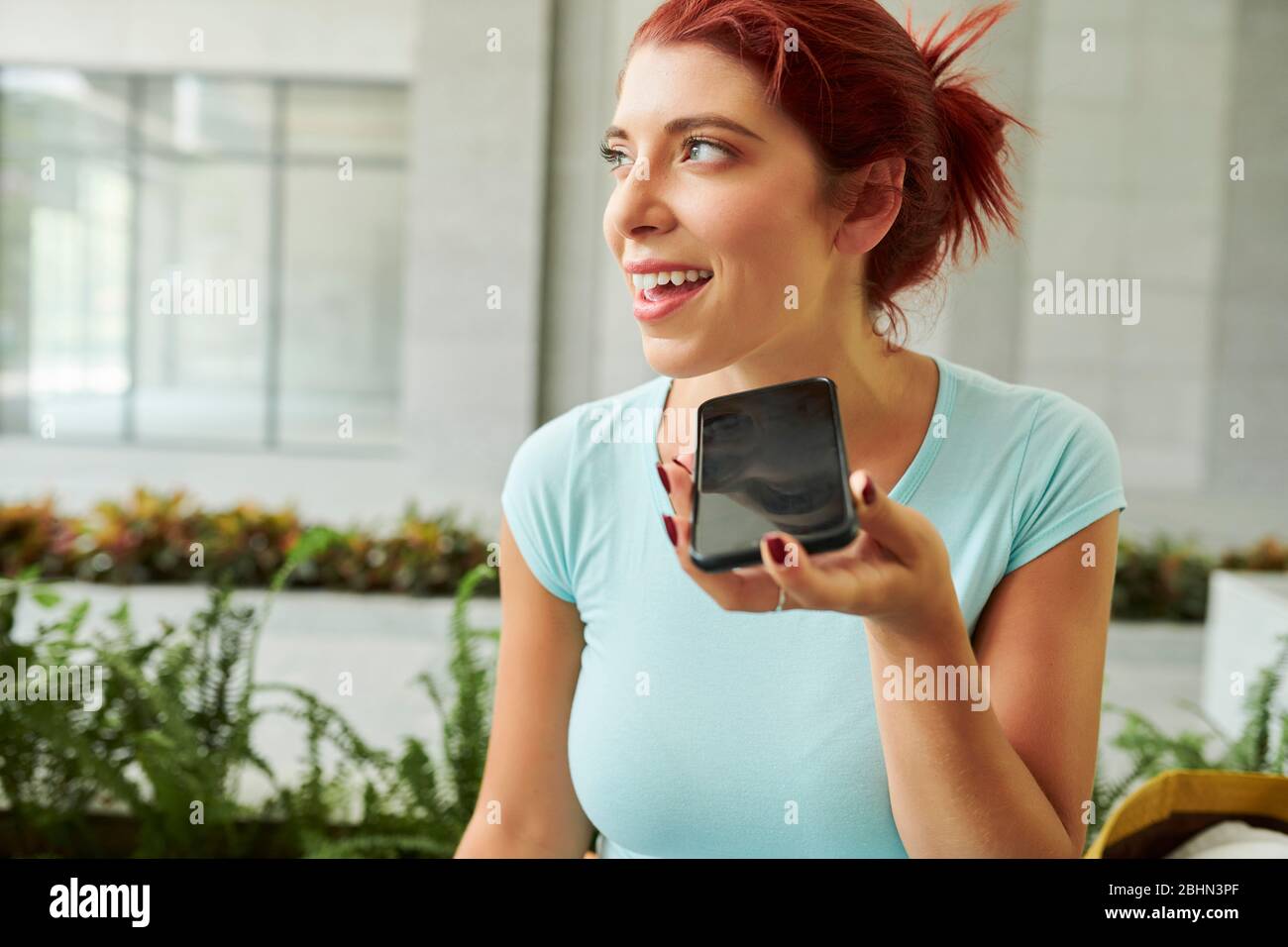 Pretty excited young woman recording voice message for her colleague or ...