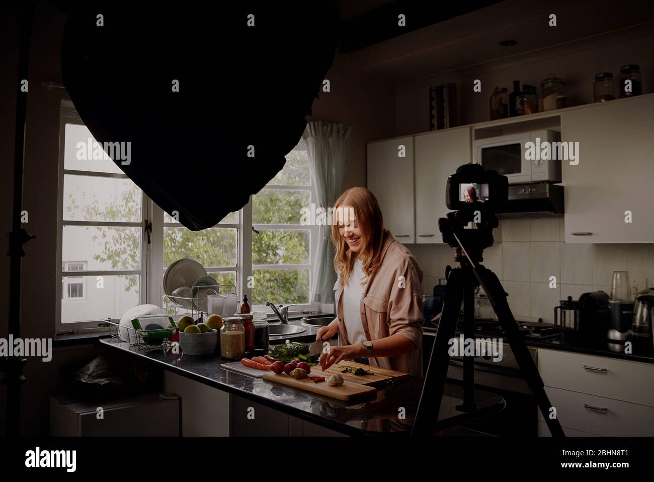 Female food vlogger recording video on dslr camera while chopping ...
