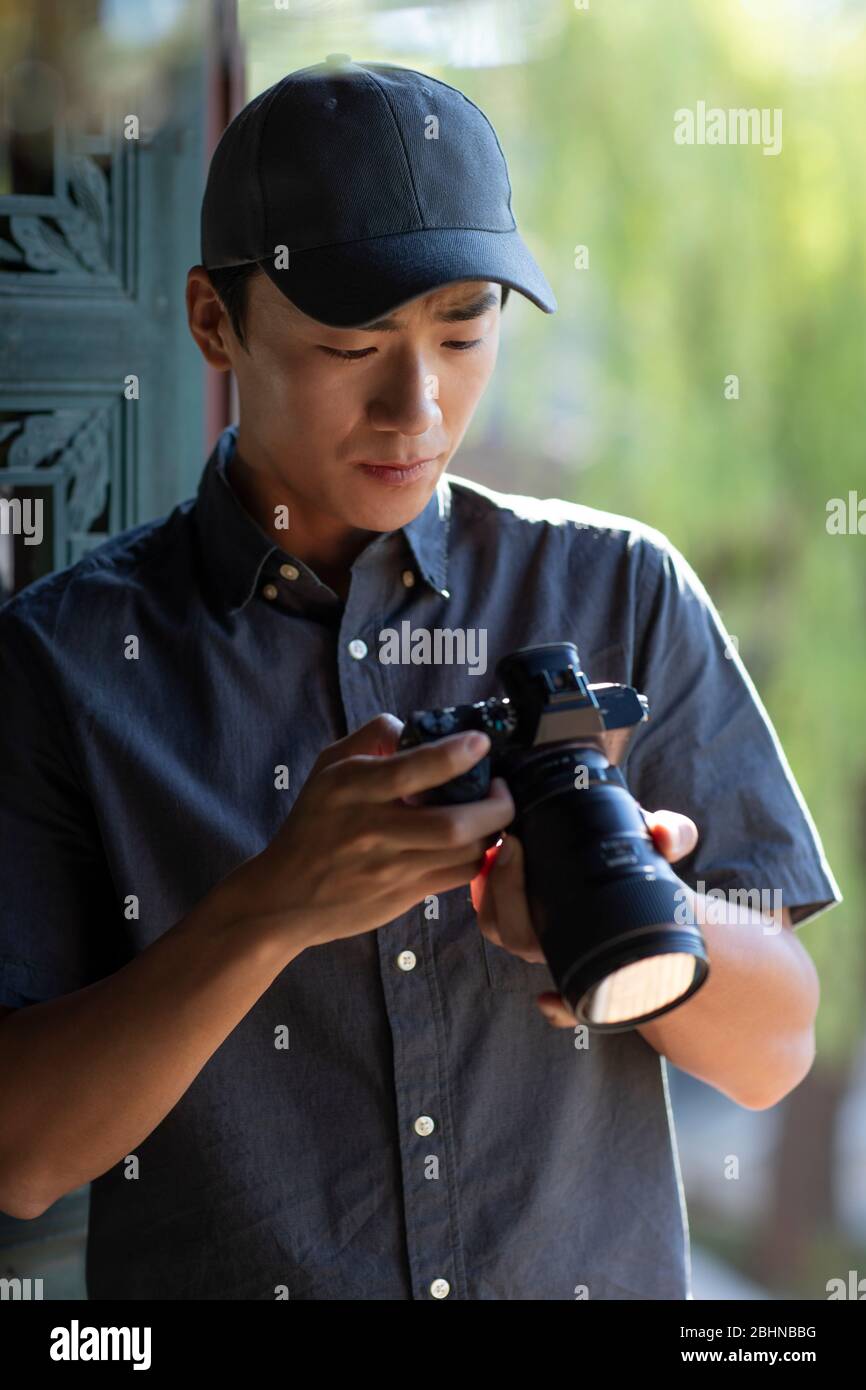Young Chinese photographer examining photos on camera Stock Photo - Alamy