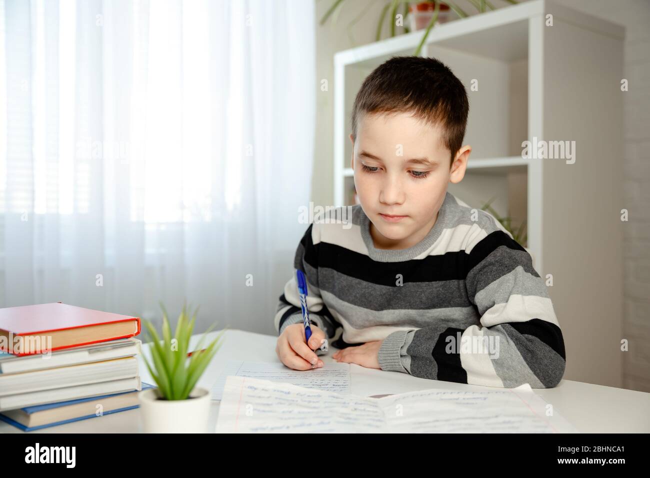Cute school kid boy at home making homework. Child writing Stock Photo ...