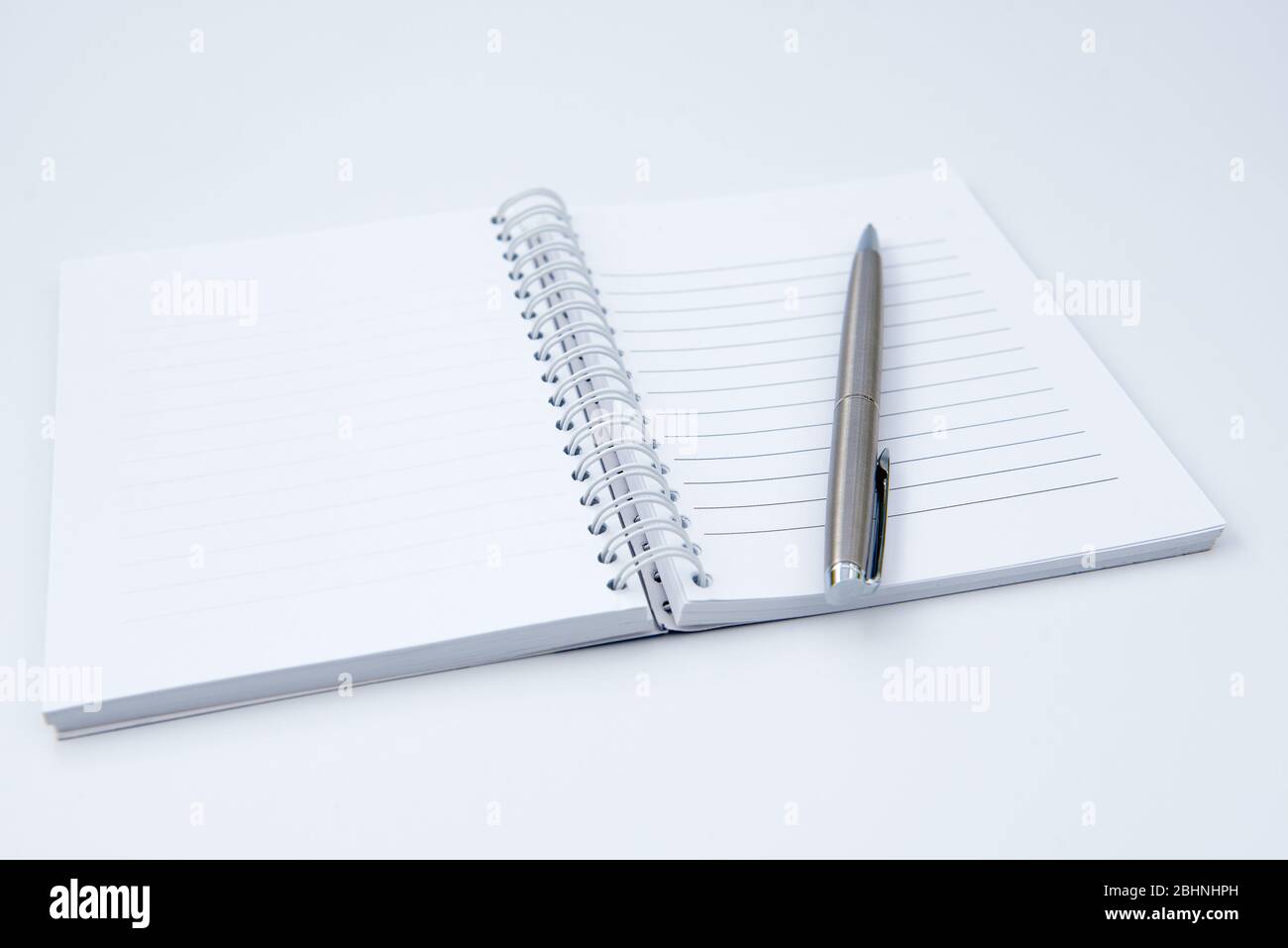 Open notebook with a pen on a white office table Stock Photo - Alamy