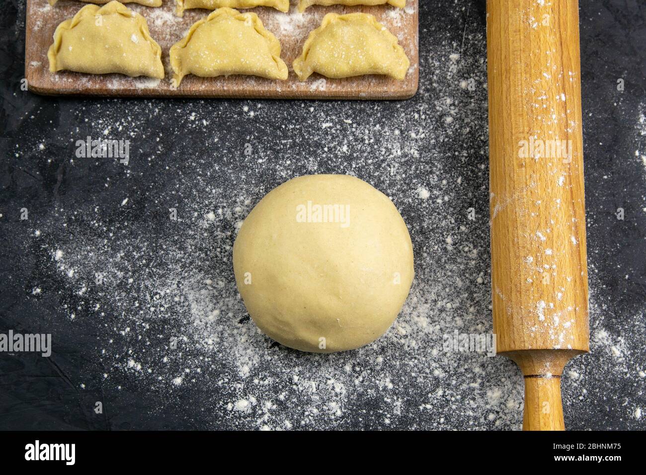 Dumplings in flour on the wooden board, hand holding Dough before ...