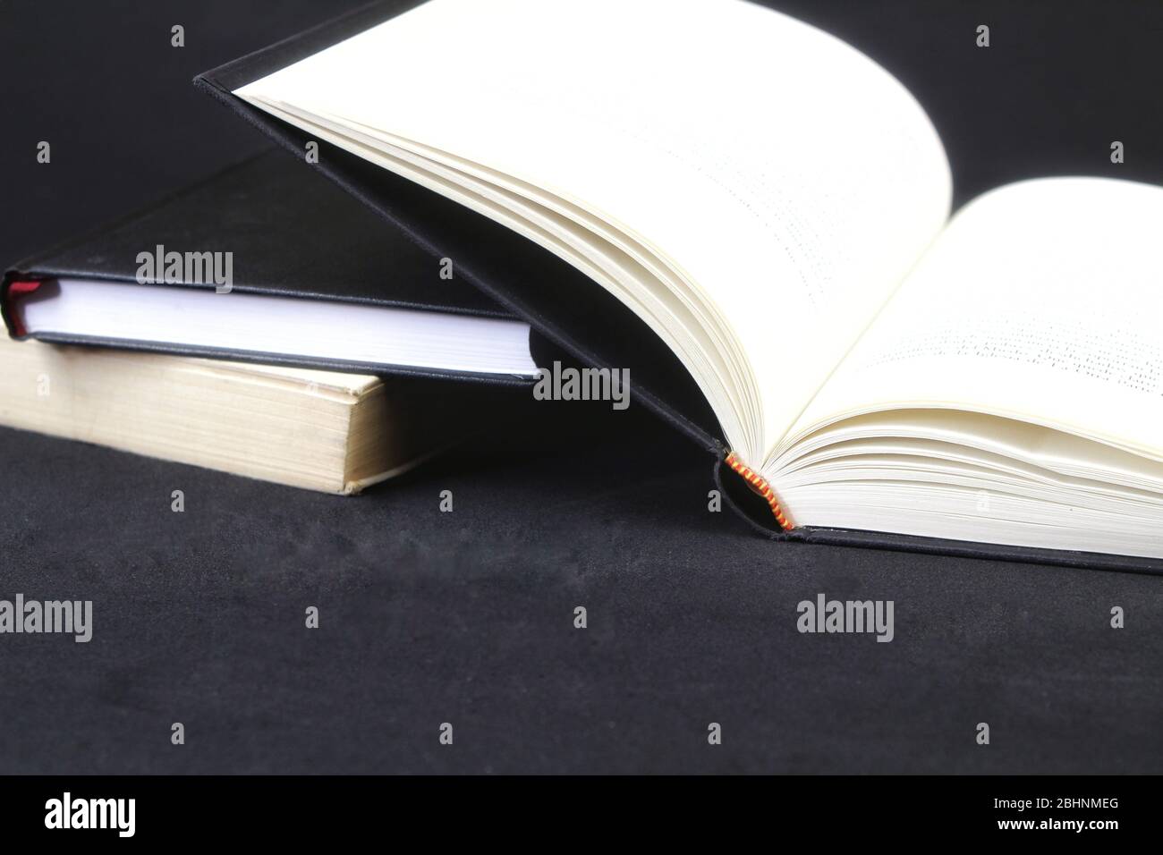 Black book opened on black background Stock Photo - Alamy