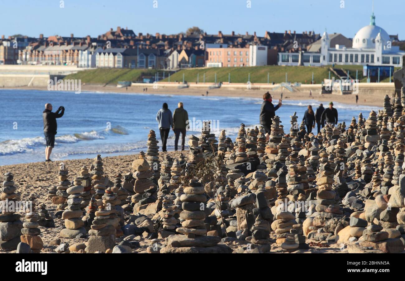 People photograph the pebble stacks on the beach at Whitley Bay which ...