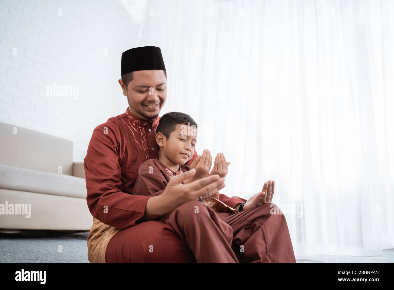 Muslim father and son praying together at home Stock Photo - Alamy