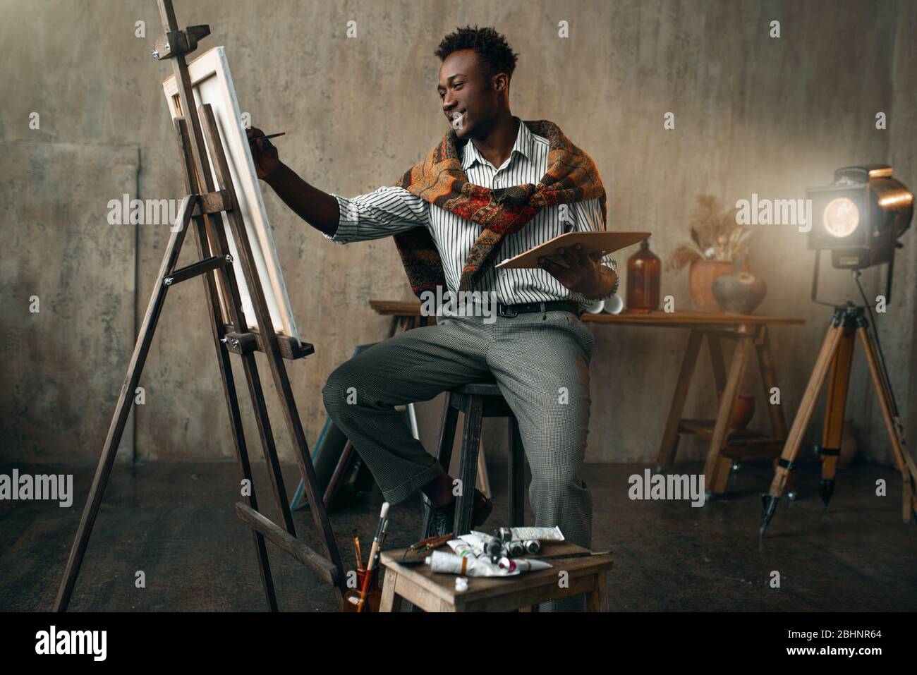 Smiling painter with brush and palette at easel Stock Photo - Alamy