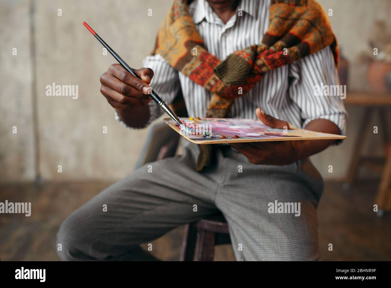 Smiling painter with brush and palette at easel Stock Photo - Alamy