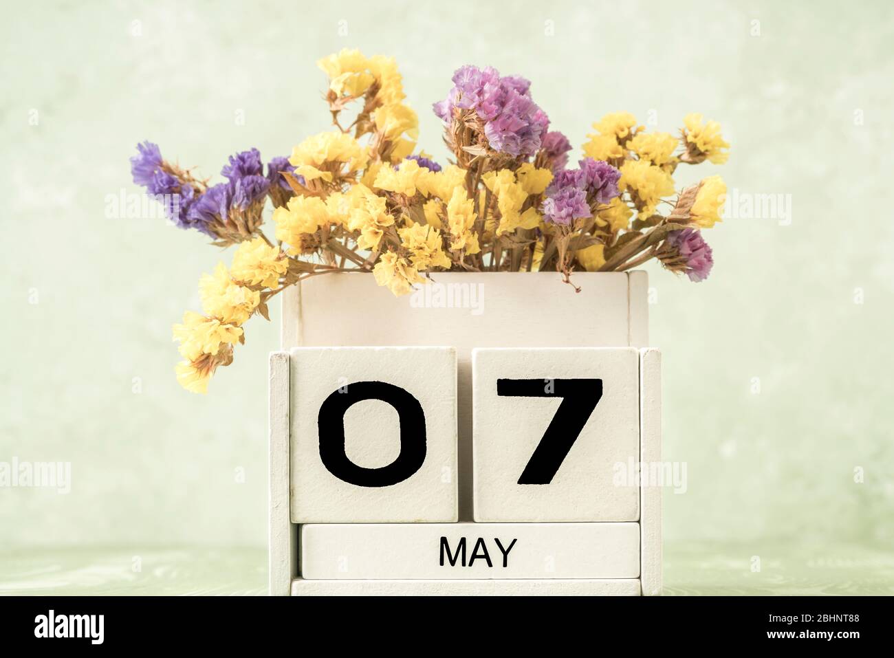 White cube calendar for may decorated with flowers over green ...