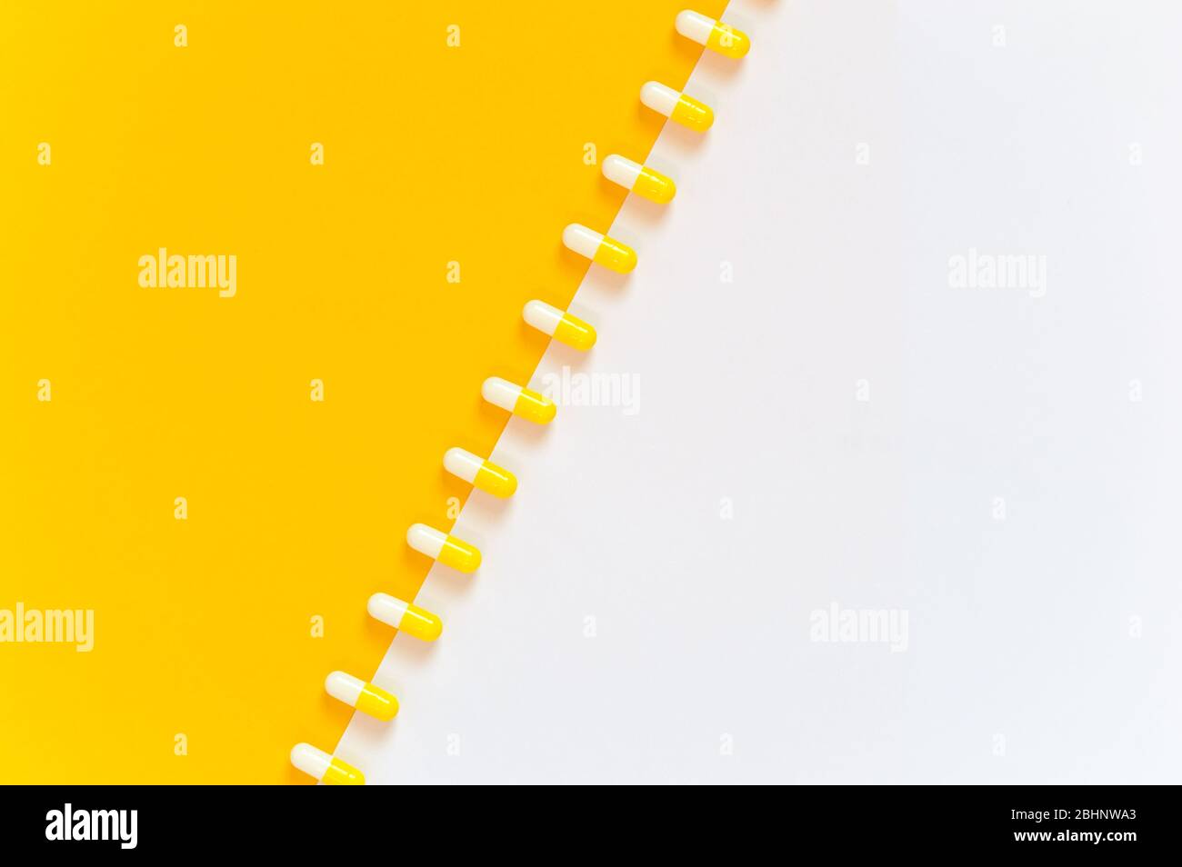 Row of medication capsules lined on intersection of white and yellow ...