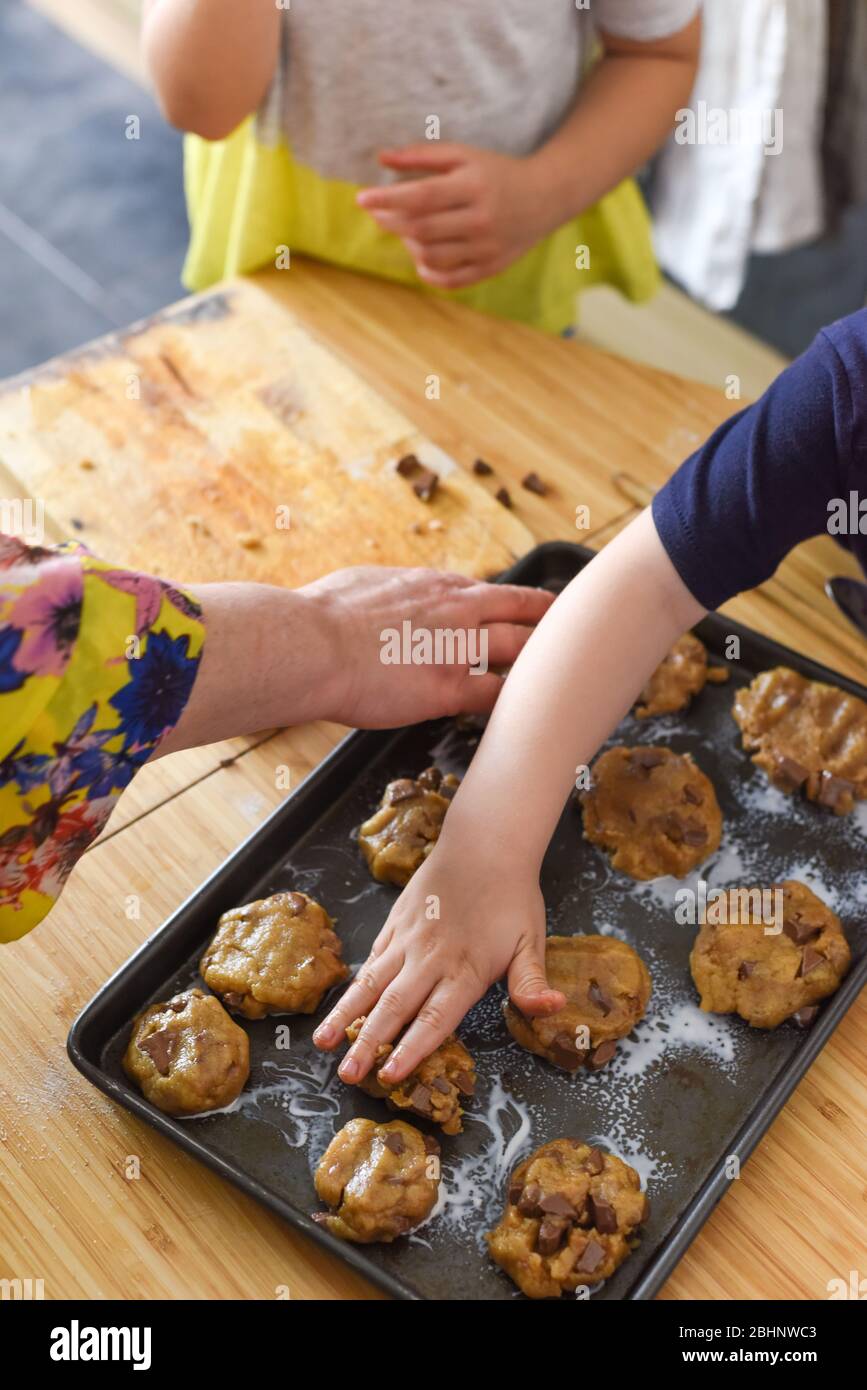 Kids making cookies in kitchen placing dough on tray for cooking at ...