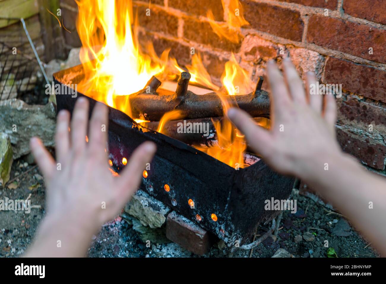 kids warming their arms over fire and grill on red brick wall ...