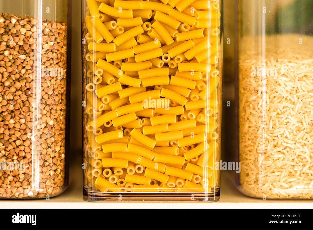raw macaroni pasta, buckwheat and basmati rice inside clear storage ...