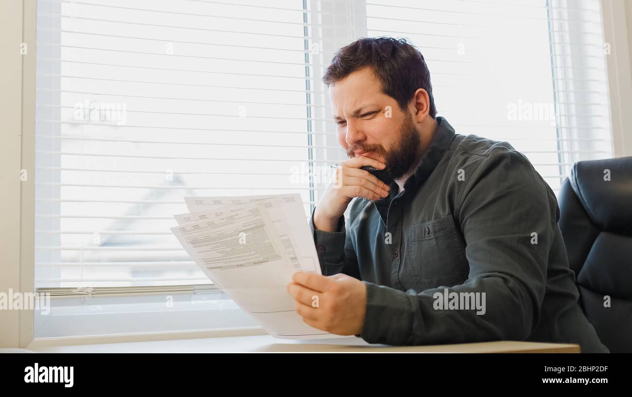 Manager reading documents at cabinet, holding papers and pen Stock ...