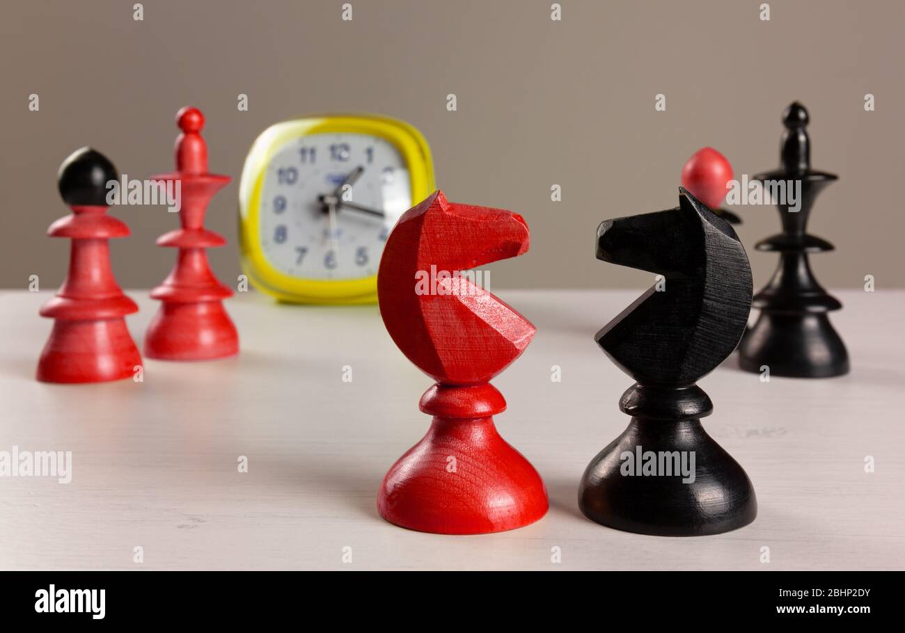 Two knights facing each other on a white wooden table, with an alarm ...