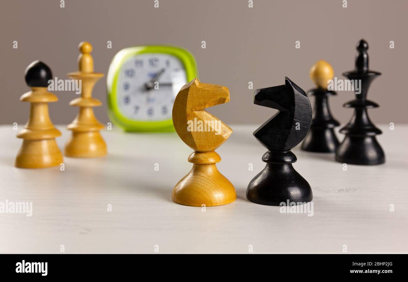 Two knights facing each other on a white wooden table, with an alarm ...