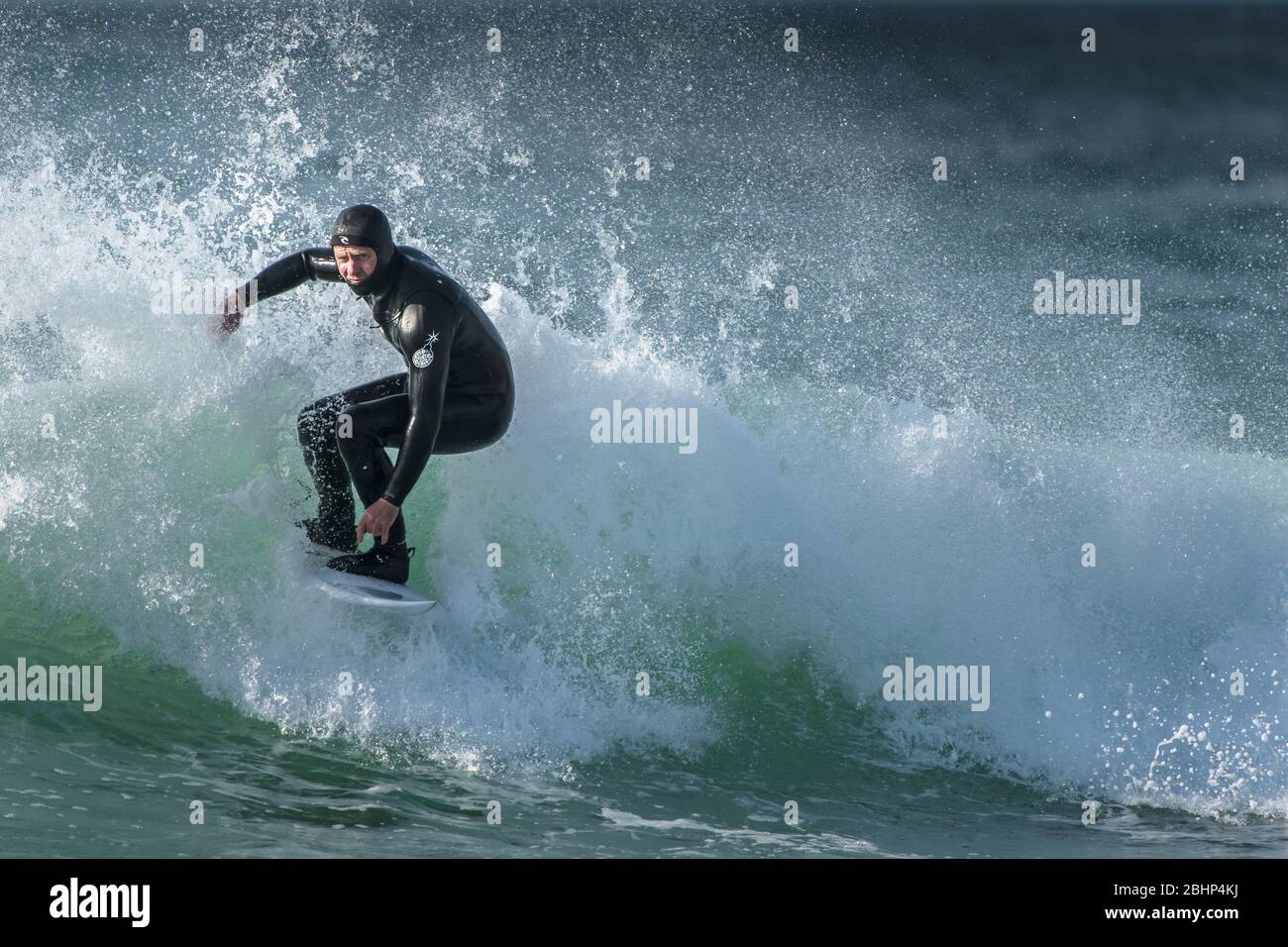Spectacular surfing action as a mature surfer rides a wave at Fistral ...