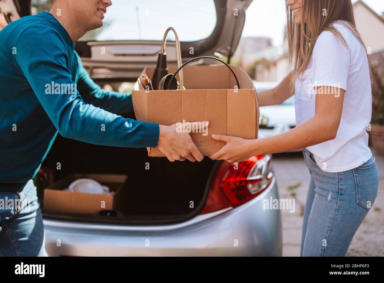Handsome caucasian couple pull boxes out of the car. Love and moving ...
