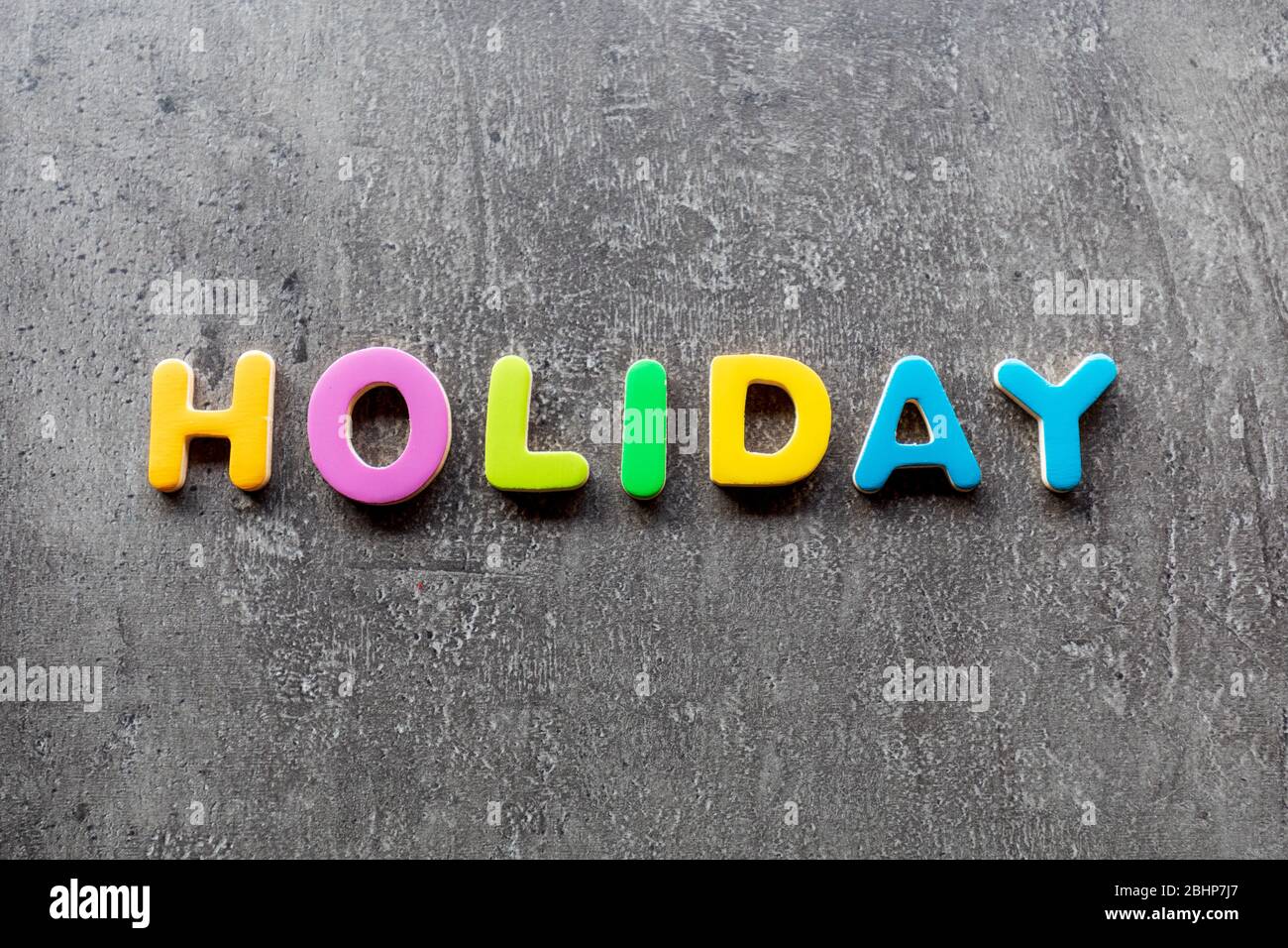 holiday word written with colorful letters on granite stone background ...