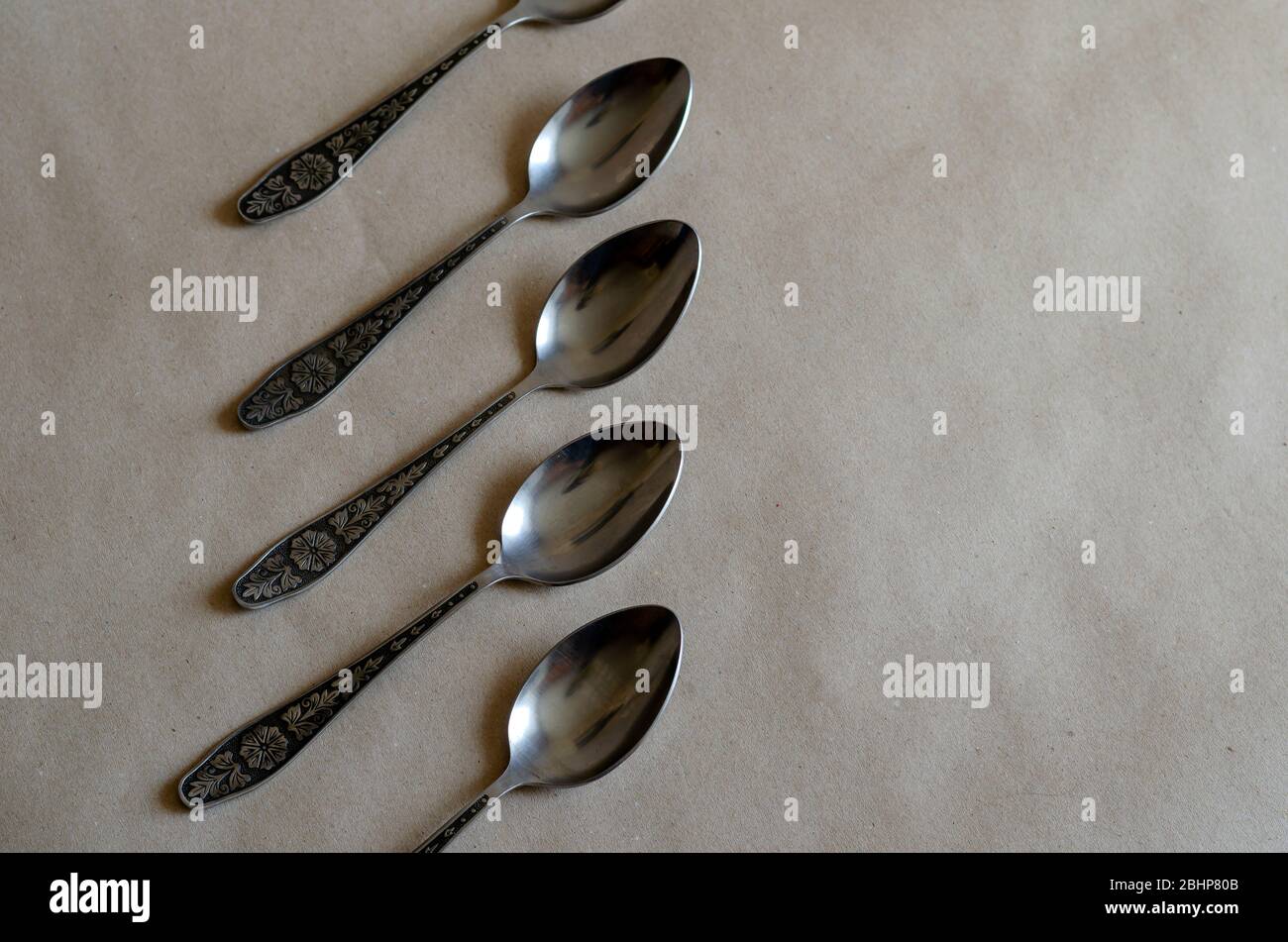 Five metal spoons on beige. Lined up spoons. Serving option. Copy space ...