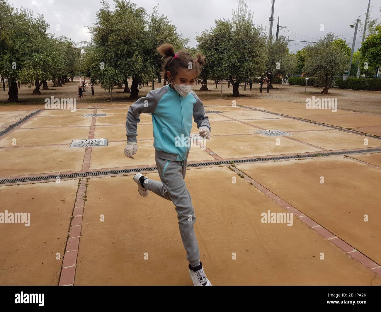 Nine-year-old girl, wearing an N95 mask, running in the street Stock ...