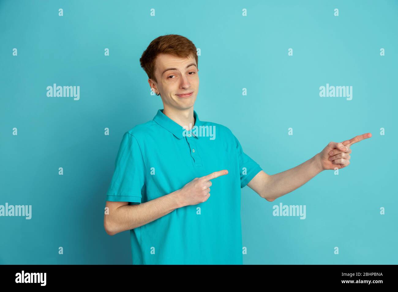 Pointing at side. Caucasian young man's modern portrait isolated on ...
