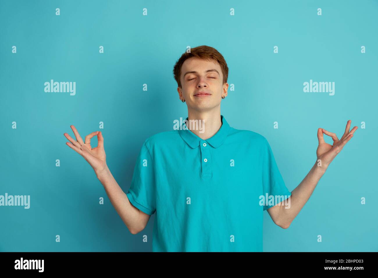Balanced, calm. Caucasian young man's modern portrait isolated on blue ...