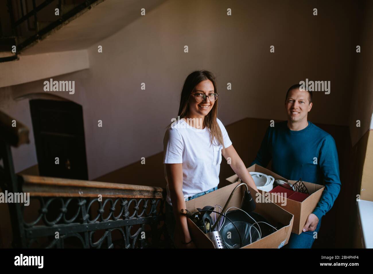 Attractive caucasian boyfriend and girlfriend carrying boxes with ...