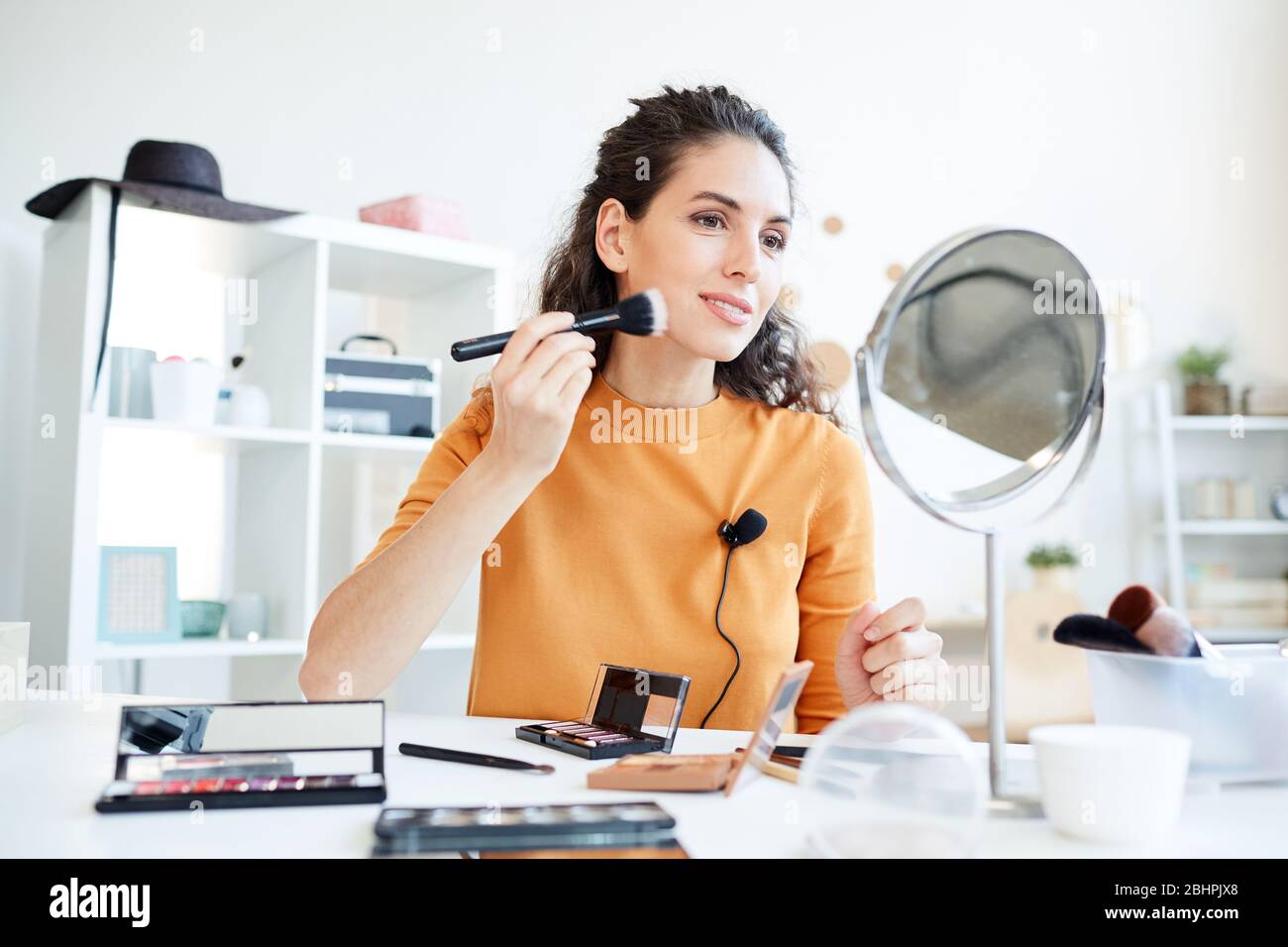 Beauty blogger applying contouring powder on her face using make-up ...