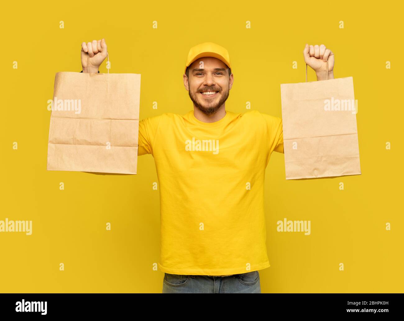 Man in yellow cap, t-shirt giving empty paper packets isolated on ...