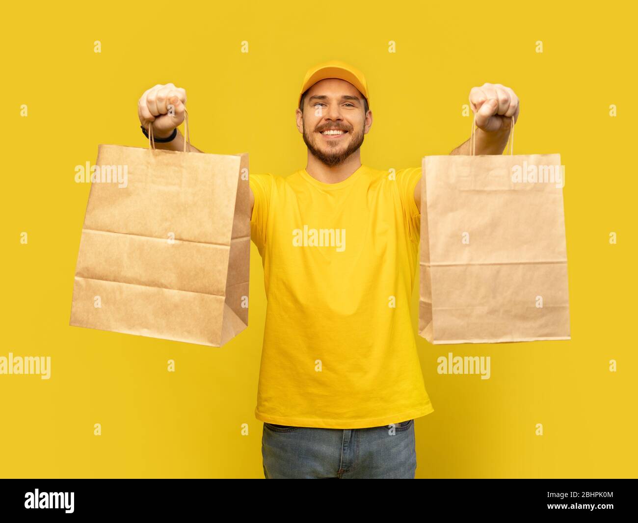 Man in yellow cap, t-shirt giving empty paper packets isolated on ...