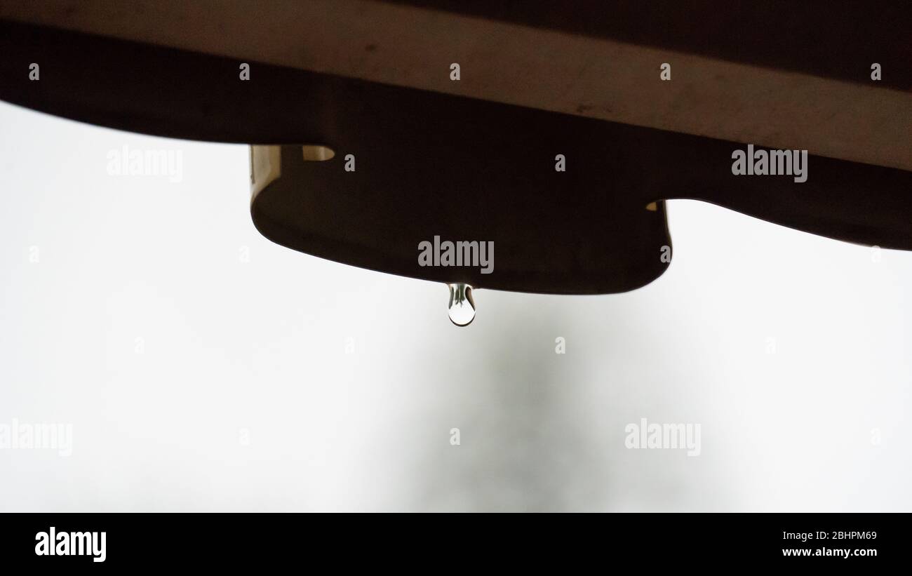 Single clear rain drop hanging from the edge of a roof Stock Photo - Alamy