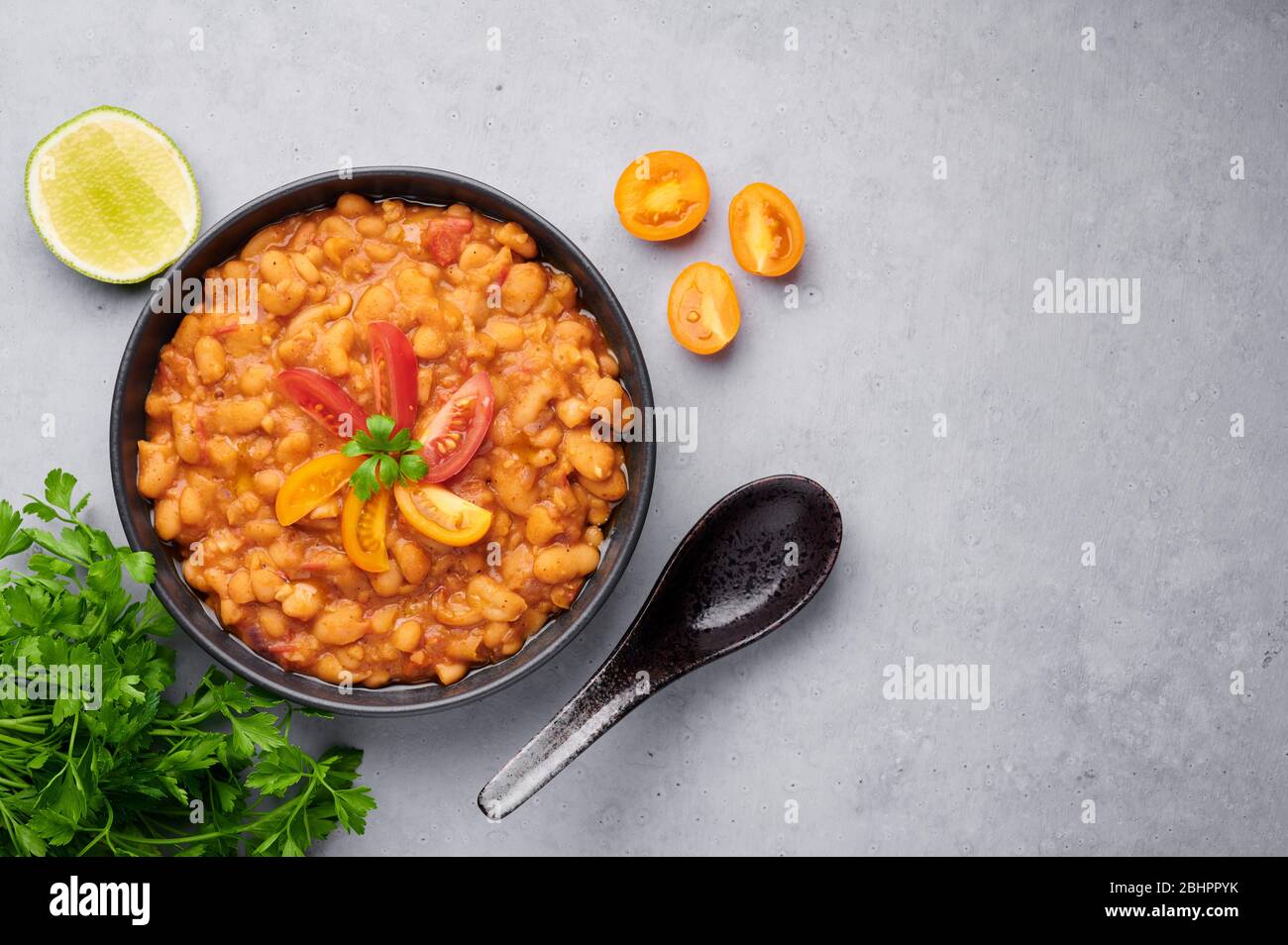 Ful Medames or Fava Beans in black bowl at grey backdrop. Foul Mudammas ...