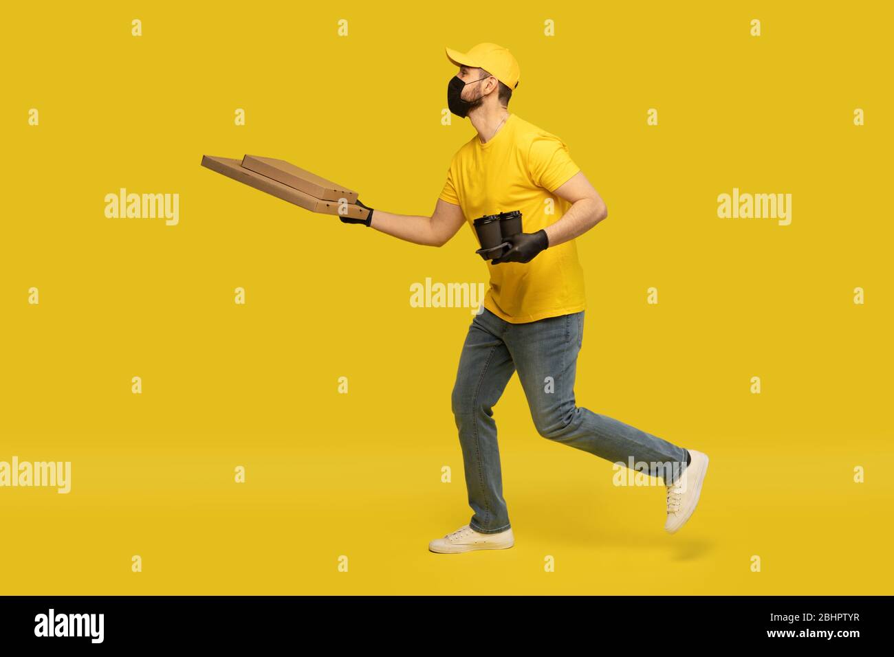 Young delivery man in yellow uniform running with pizza boxes and ...