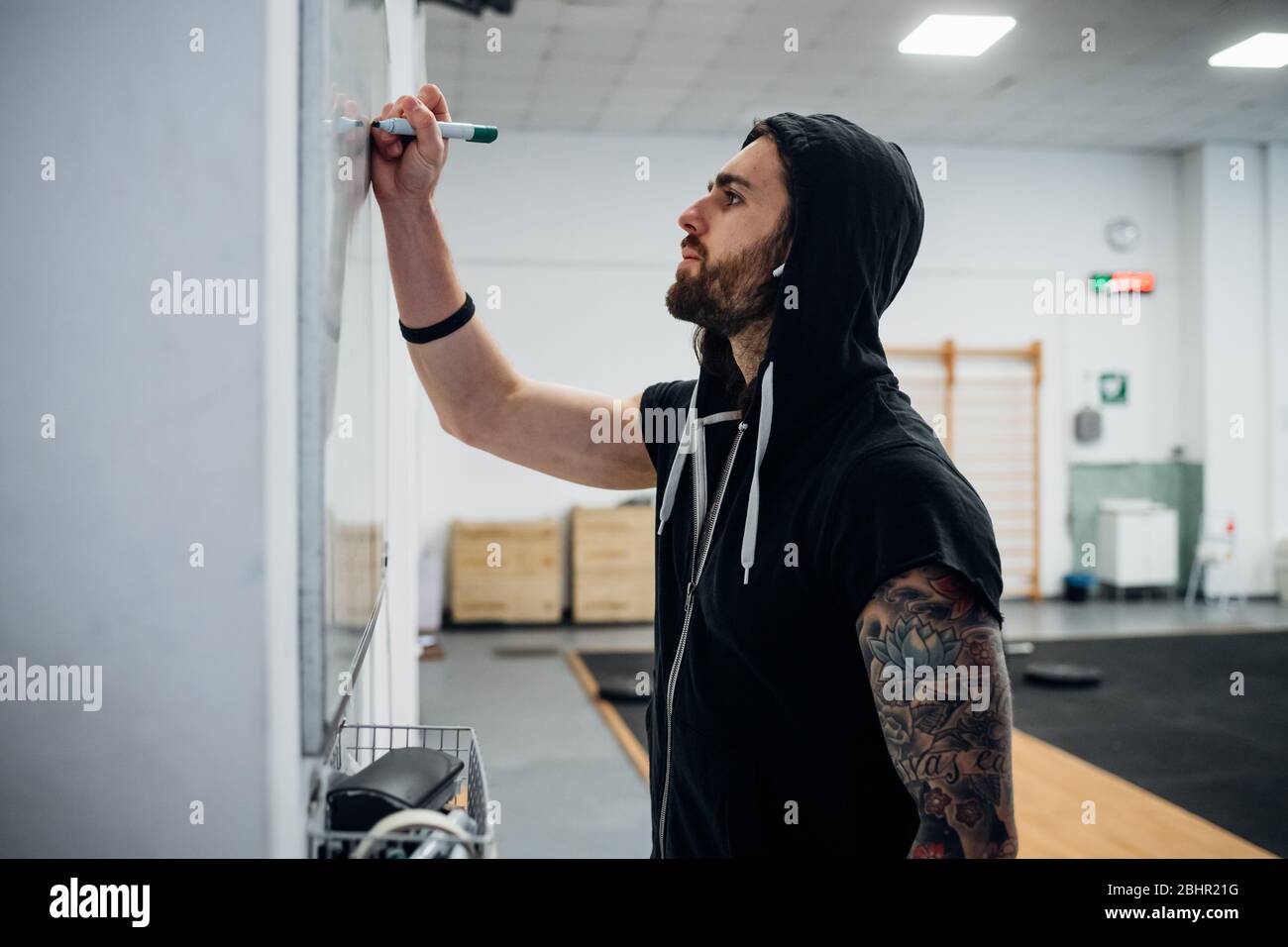 Man standing in a gym writing on a whiteboard Stock Photo - Alamy
