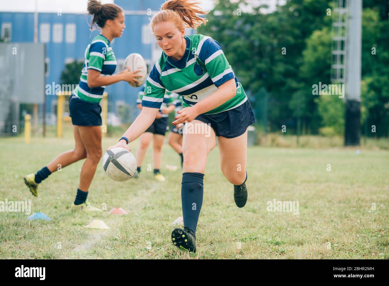 Three women wearing blue, white and green rugby shirts on a training ...