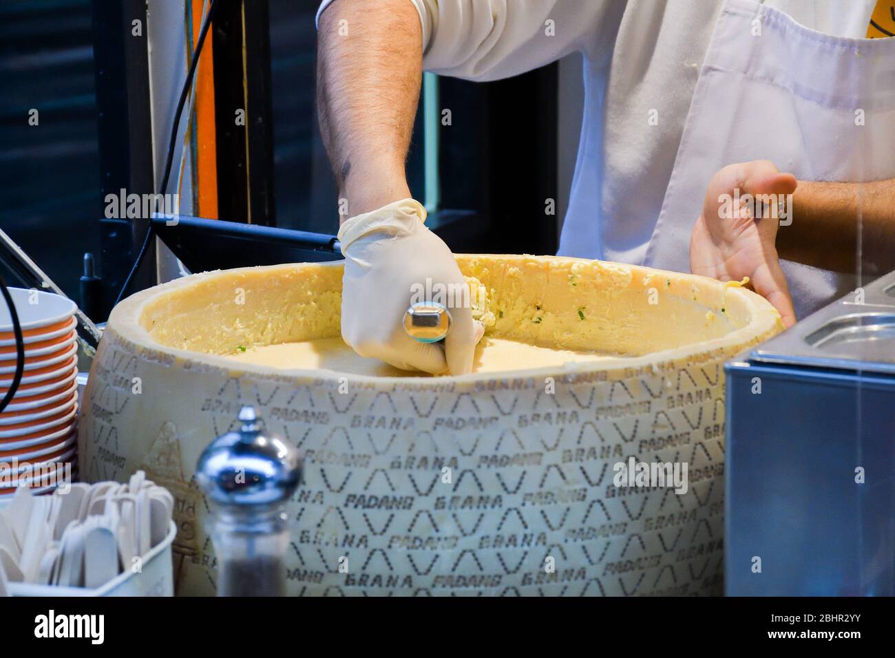 Hand scooping with a spatula a wheel of parmiggiano (parmesan Stock ...