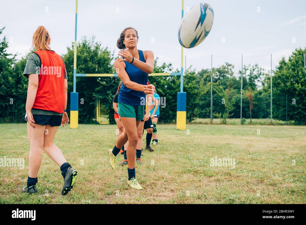Women on a training pitch one throwing a rugby ball toward the camera ...