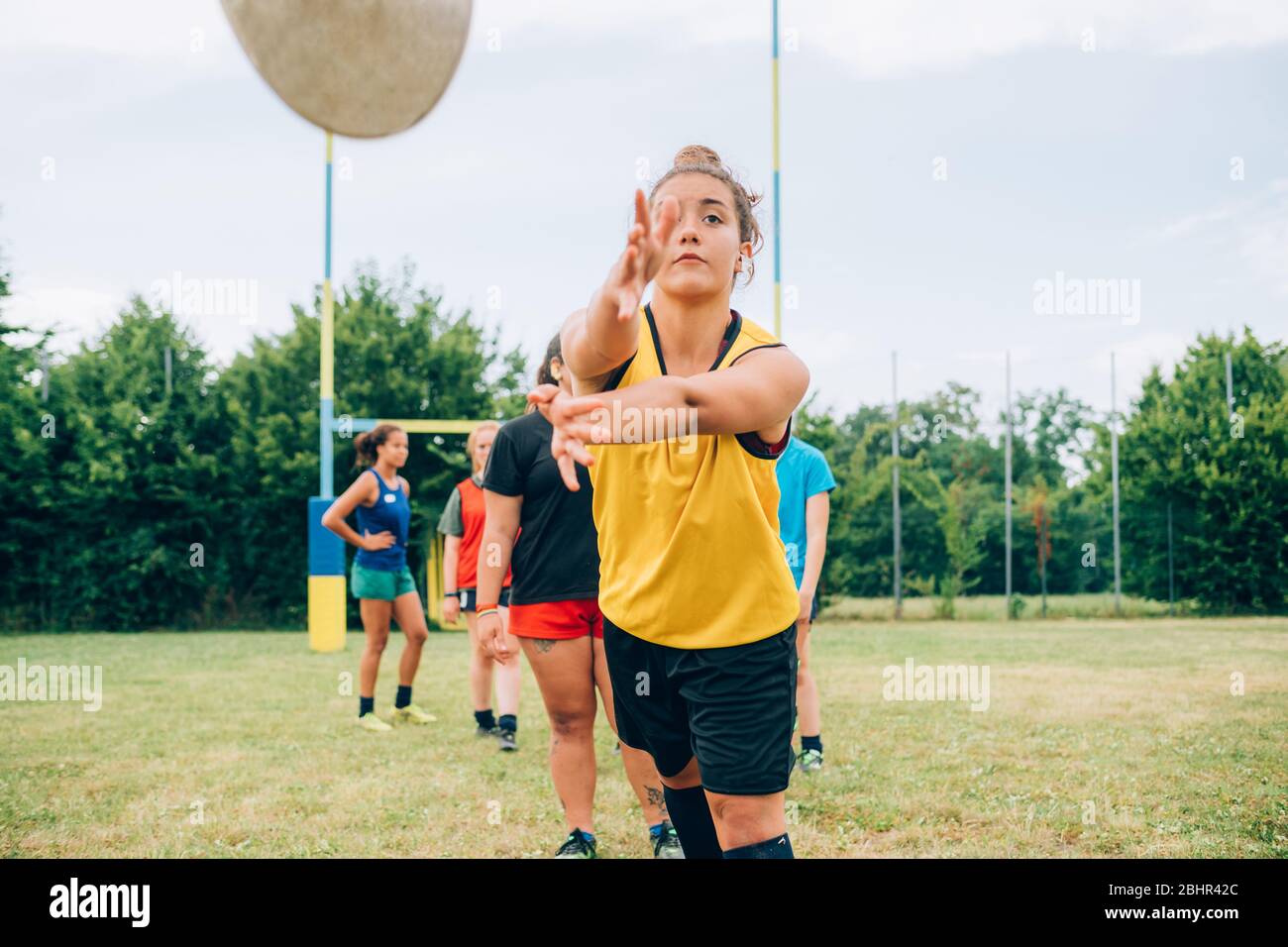 Women on a training pitch one throwing a rugby ball toward the camera ...