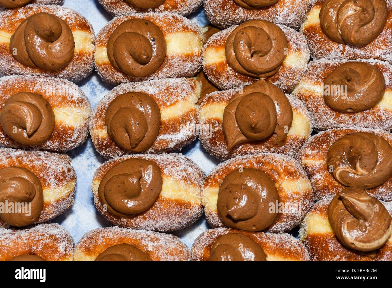 Many donuts placed in a tray, for sale at food market. Close up donuts ...