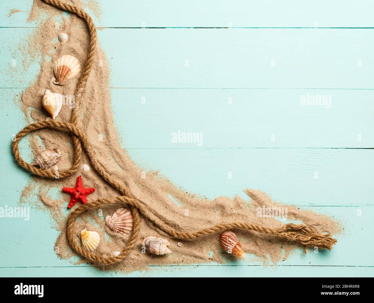 Sea rope with many different sea shells on the sea sand on a blue ...