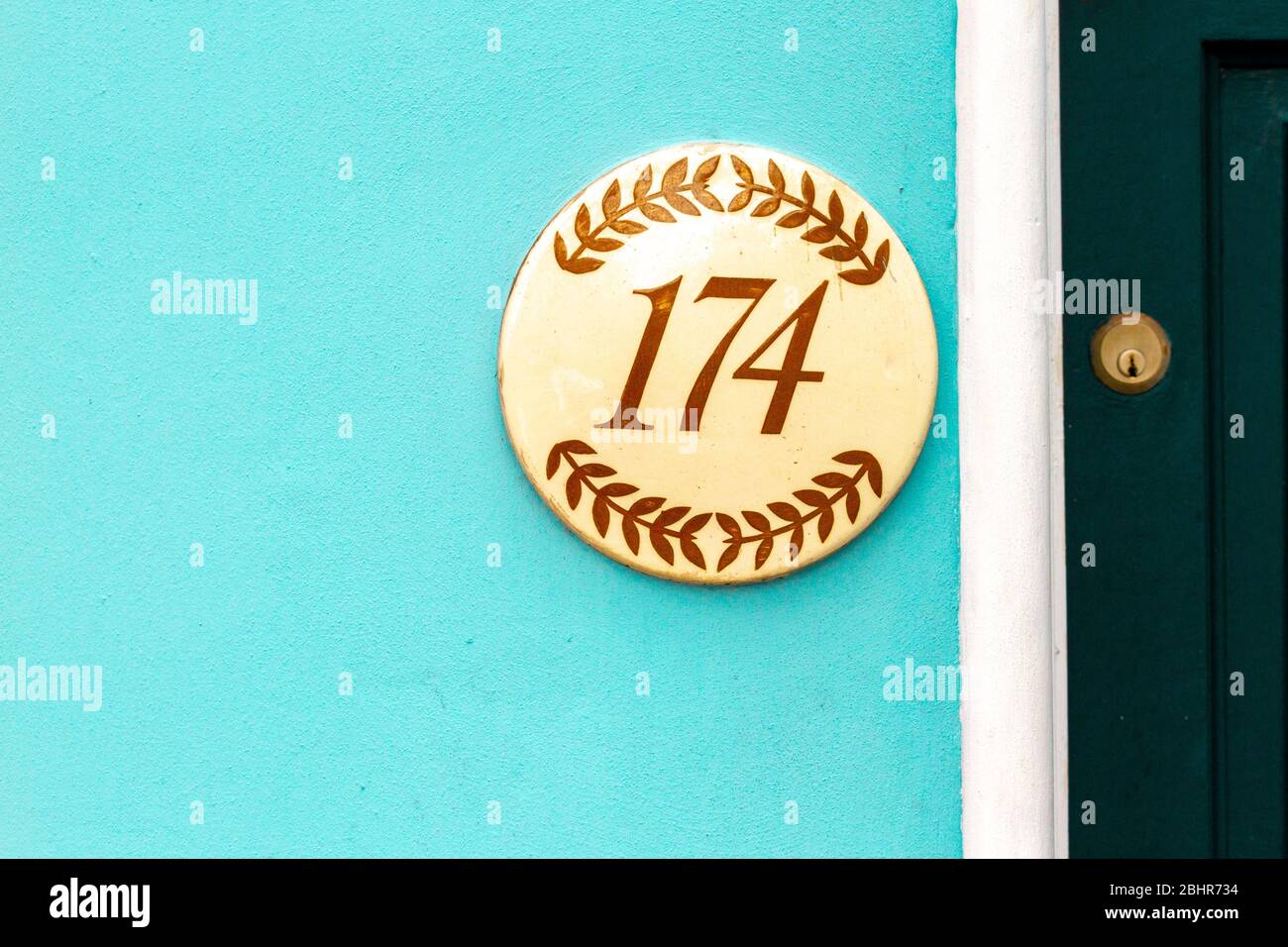 House number 174 on a round sign with laurel painted on Stock Photo - Alamy