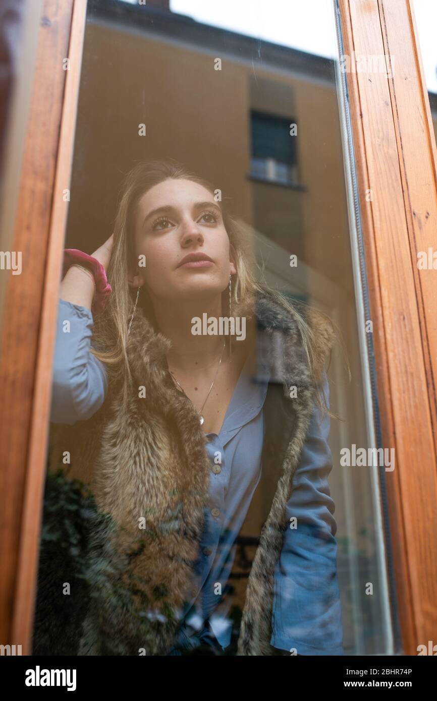 A woman looking out of a window with her hand on her head Stock Photo ...