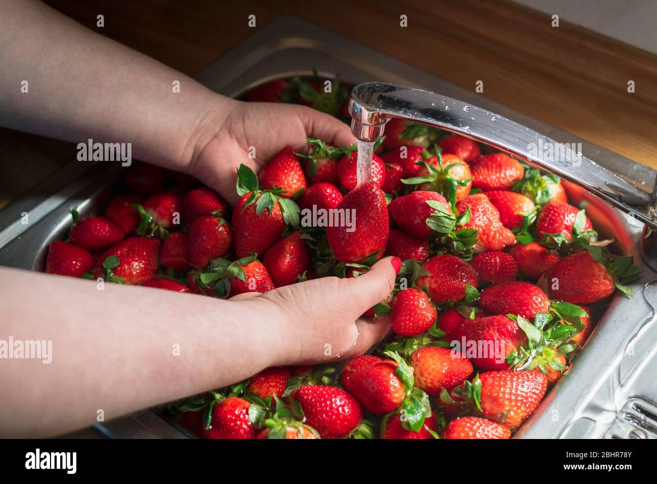 Woman's handwashing fruits in the sink with under running water ...