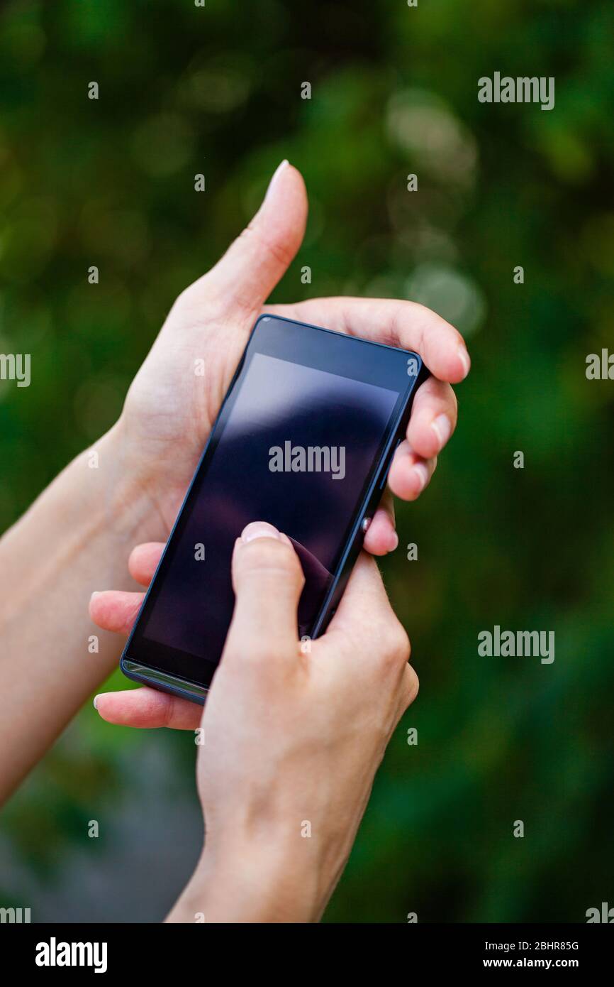 Side view of a woman's hand holding a modern slick smartphone while ...