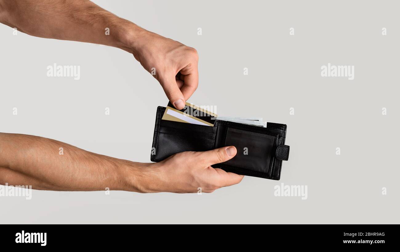 Young guy taking credit card out of wallet on light grey background ...